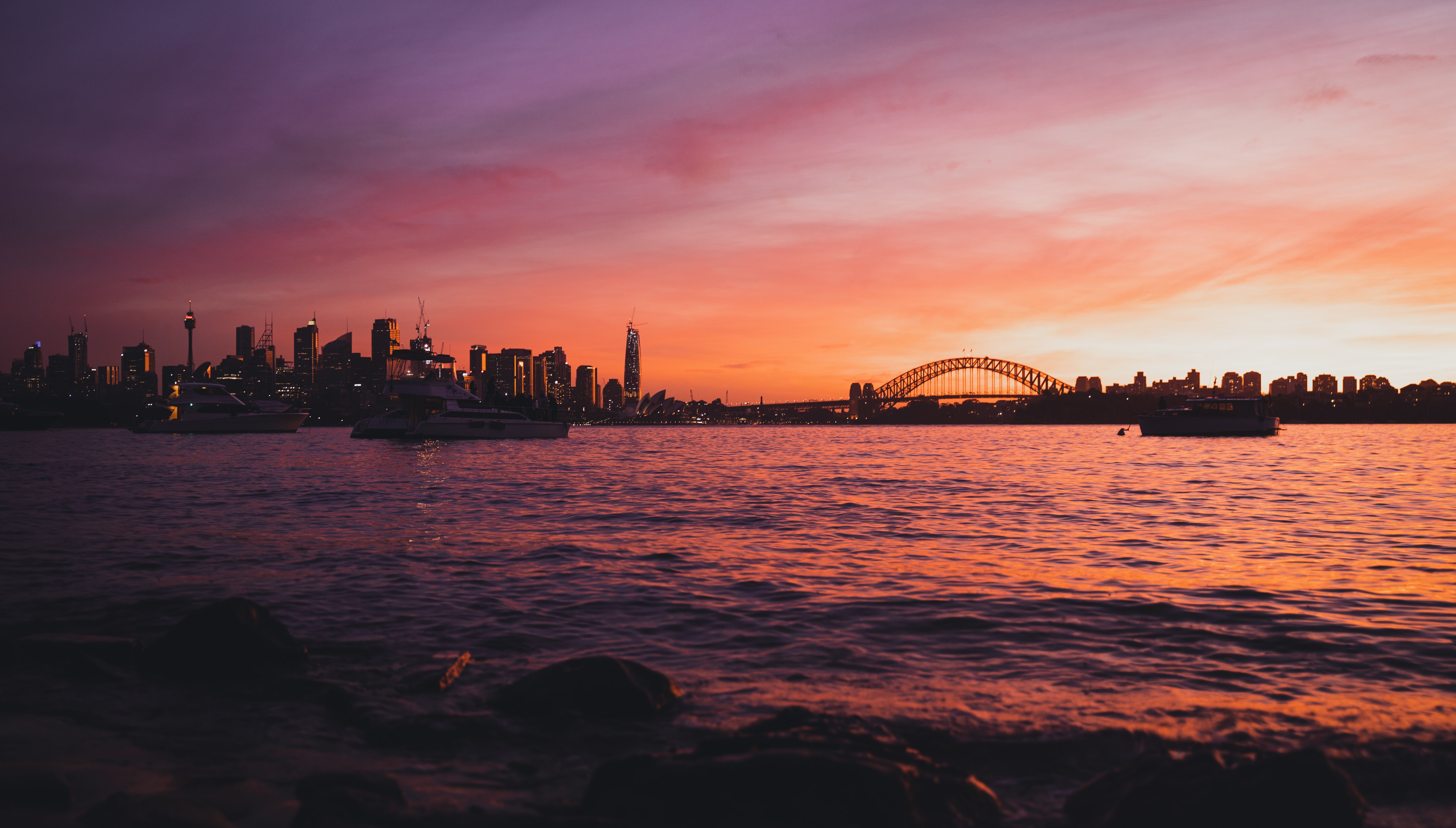 Download wallpaper 5661x3221 bridge, city, sunset, sea, waves hd background